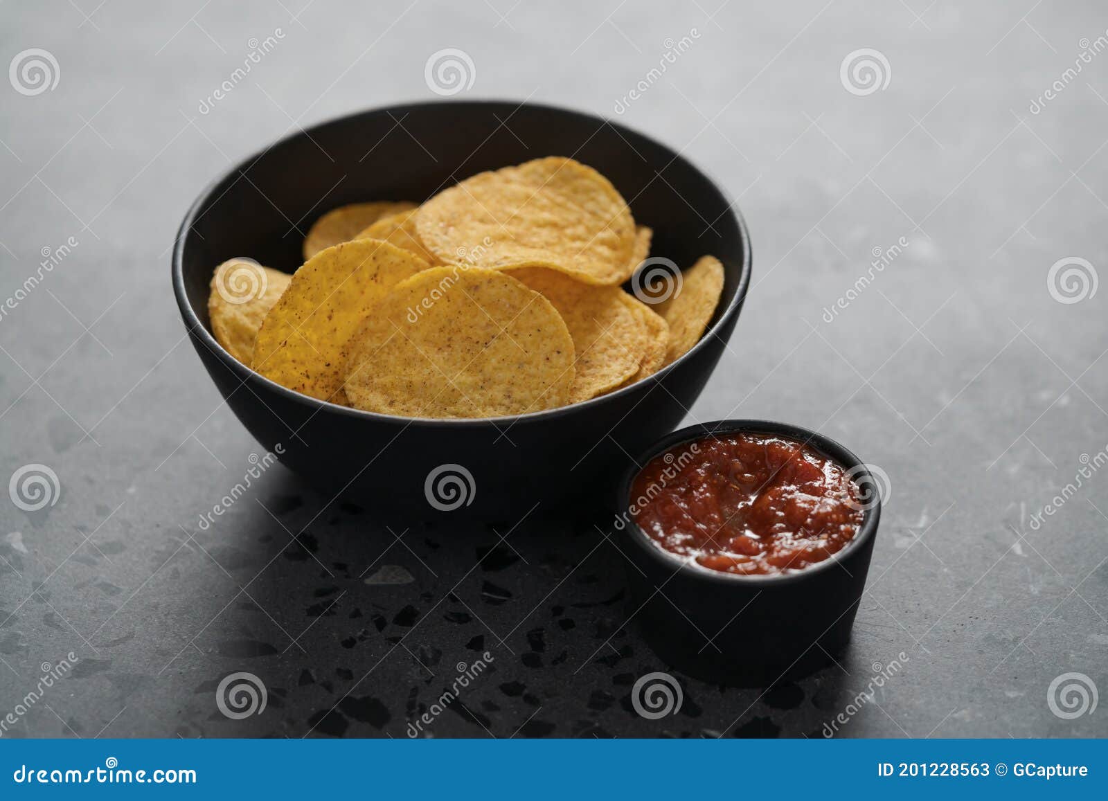 Round Nachos in Black Ceramic Bowl on Concrete Background with Red ...