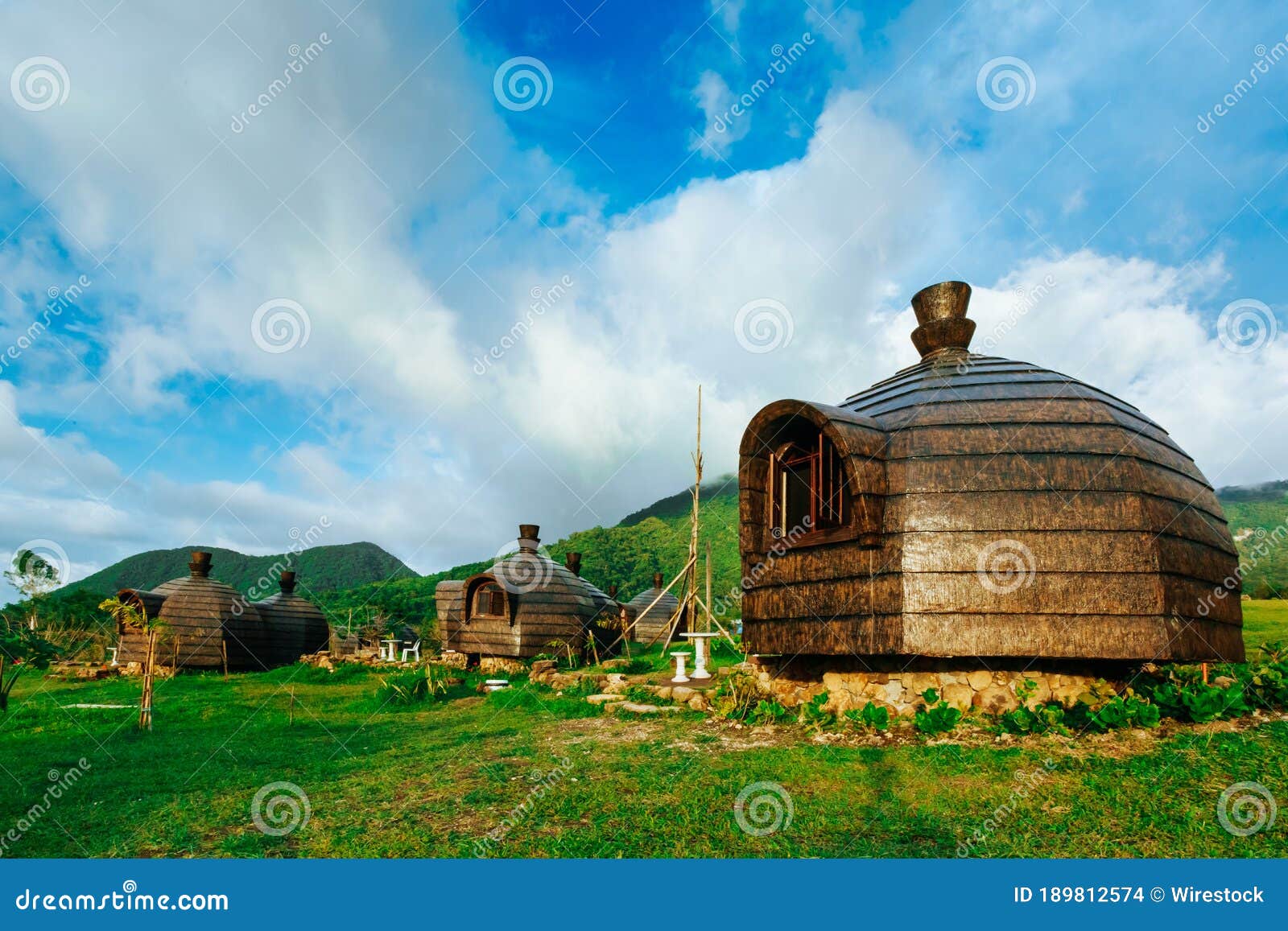 Round Small Cottages in an Open Feld Surrunded with Tree-covered Hills ...