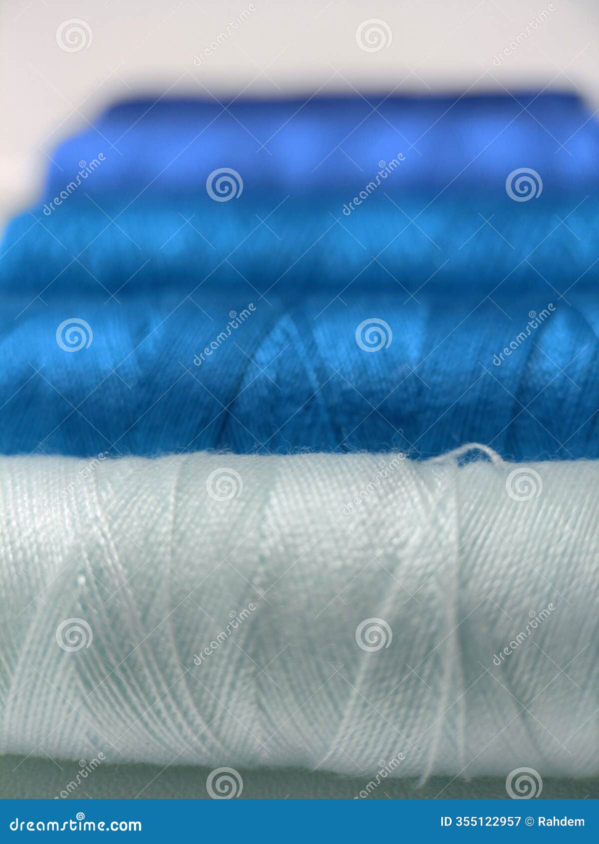 Row of Blue Sewing Thread Spools in Gradient Shades on White Background ...