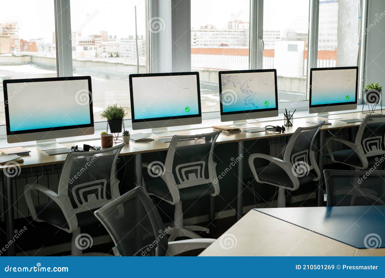 Row of Computer Monitors Standing on Desks Against Large Windows in ...
