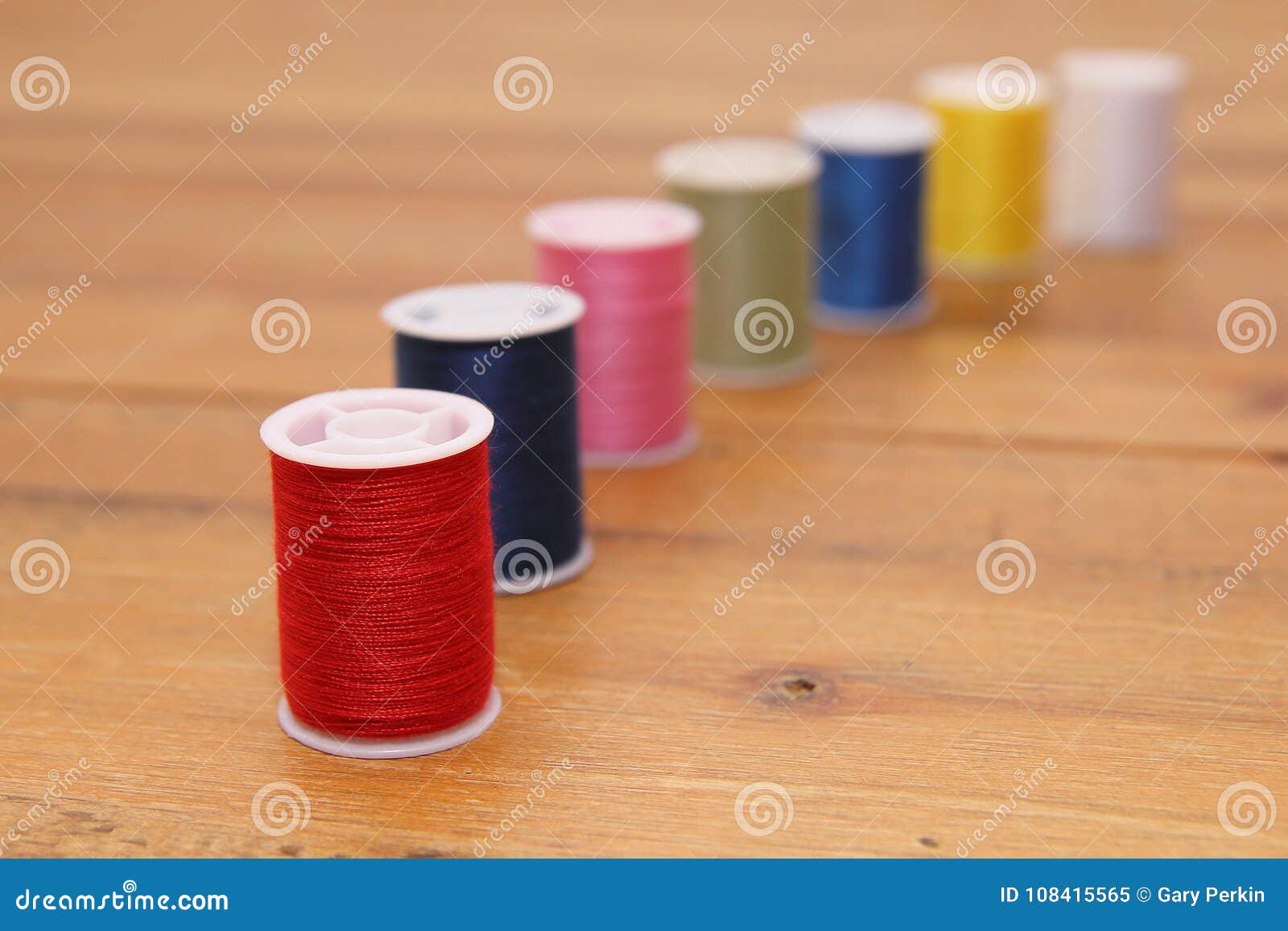 Row of Multi-colored Cotton Reels or Bobbins on a Wooden Sewing Stock ...