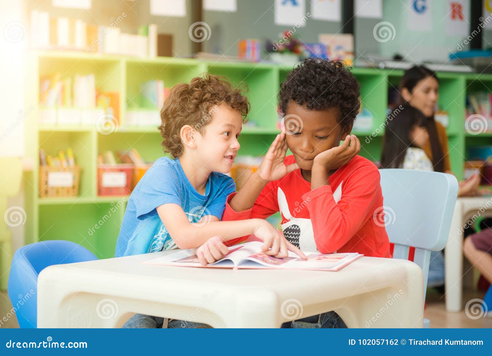 Row Of Multiethnic Elementary Students Reading Book In Classroom ...