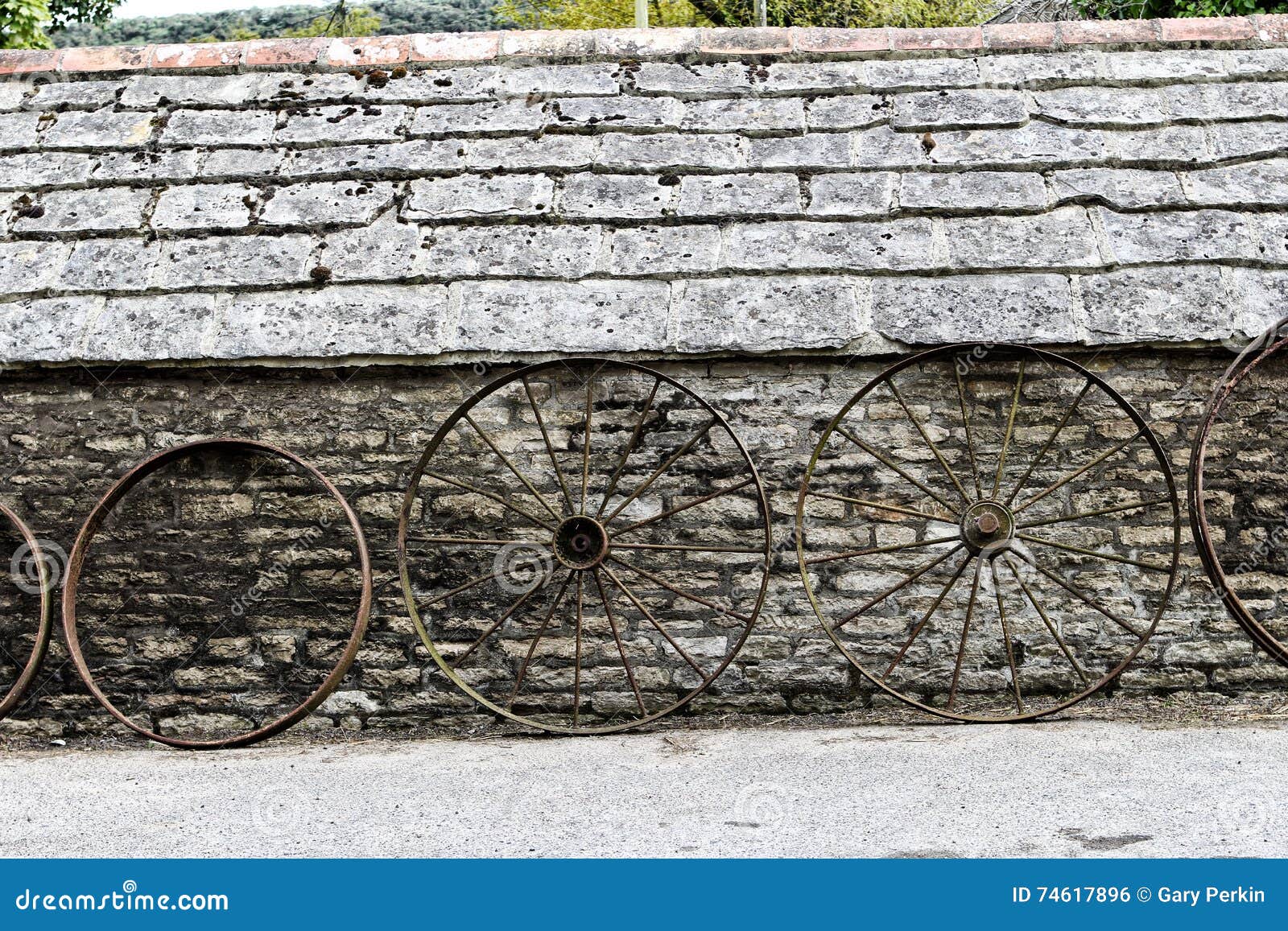 Row of Old Farm Wheels Leaning Against a Rustic Old Stone Building ...