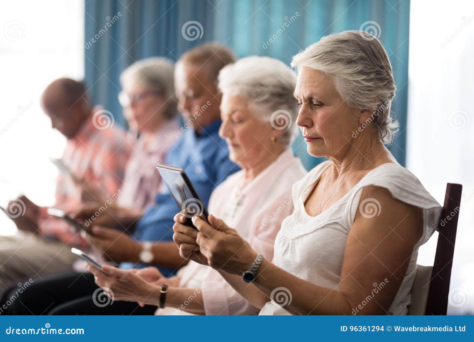 Row of Senior People Sitting on Chairs Using Digital Tablets Stock ...