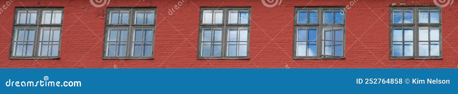 Row of Square Windows in a Red Brick Wall, Blue Sky and Clouds ...
