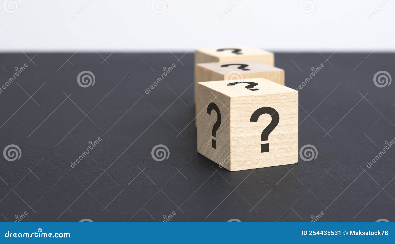 Staggered Row of Three Wooden Blocks with Question Marks on Black Table ...