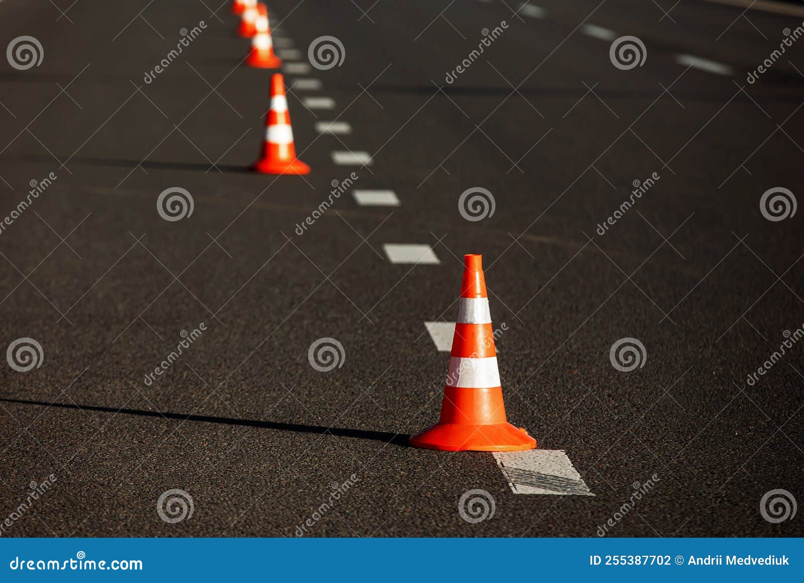 A Row of Traffic Orange Striped Cones on the Road. these Objects are ...
