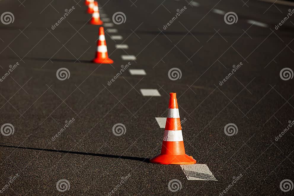 A Row of Traffic Orange Striped Cones on the Road. these Objects are ...