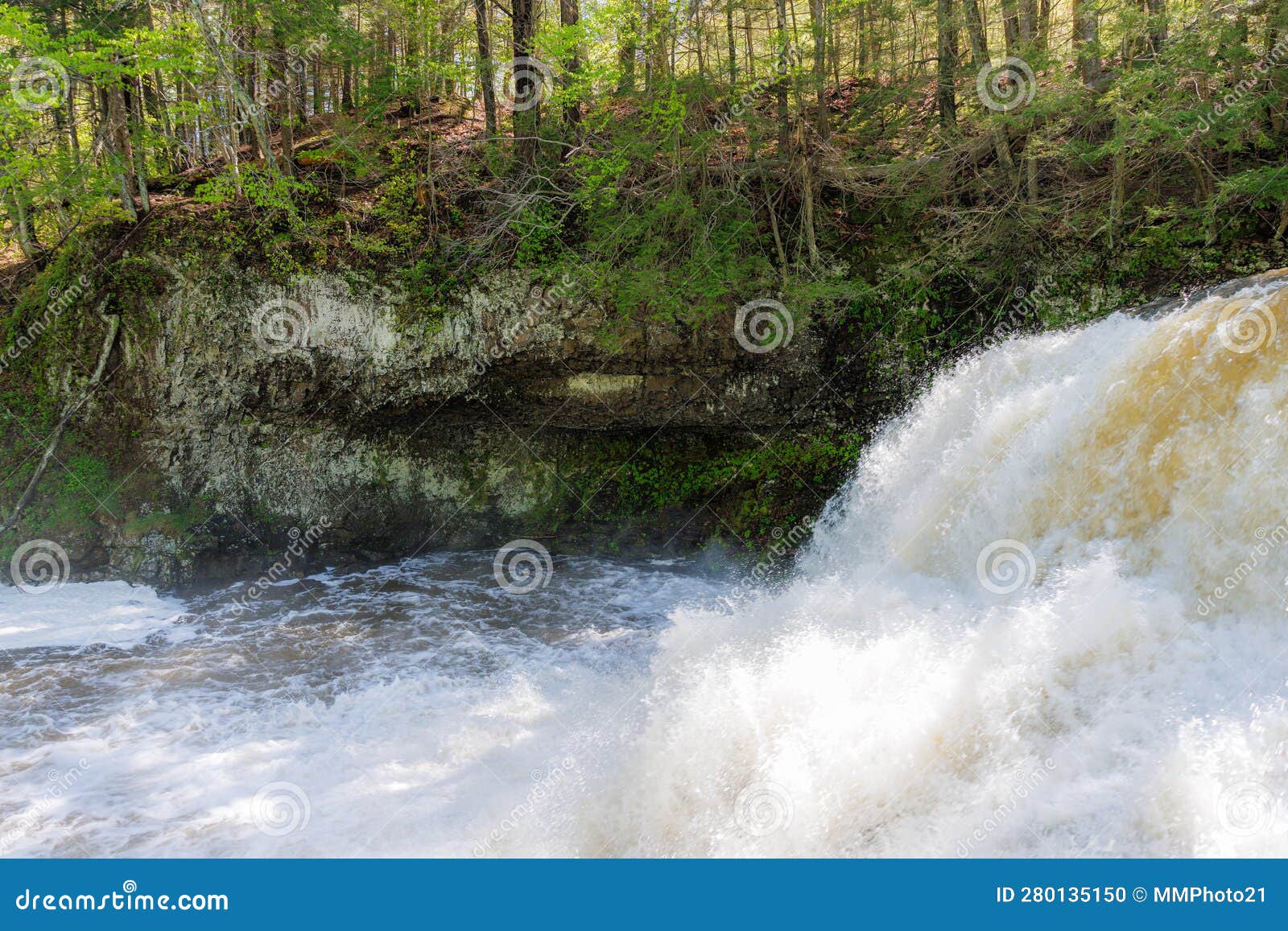 Rushing Waterfall Amidst Lush Forest Greenery and Cliff Side Rock Wall ...