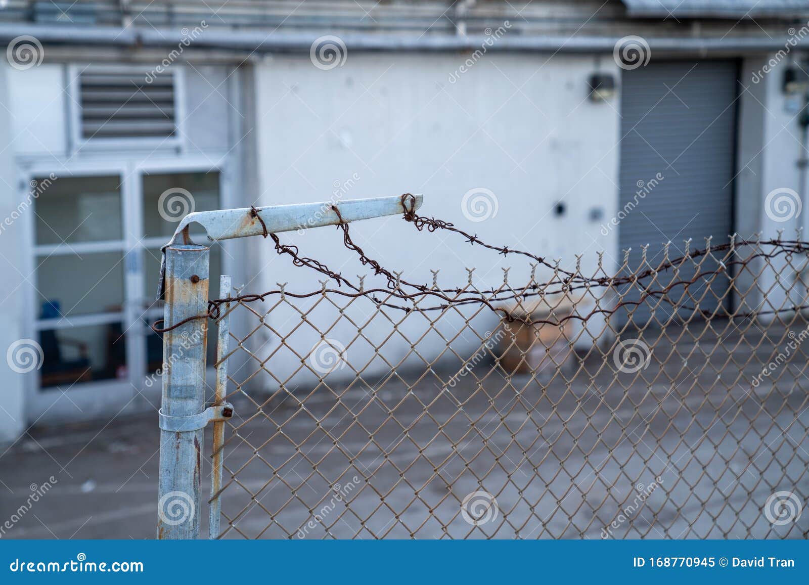 Rusted Barbed Wire on Broken Fence in Front of Warehouse Stock Image ...