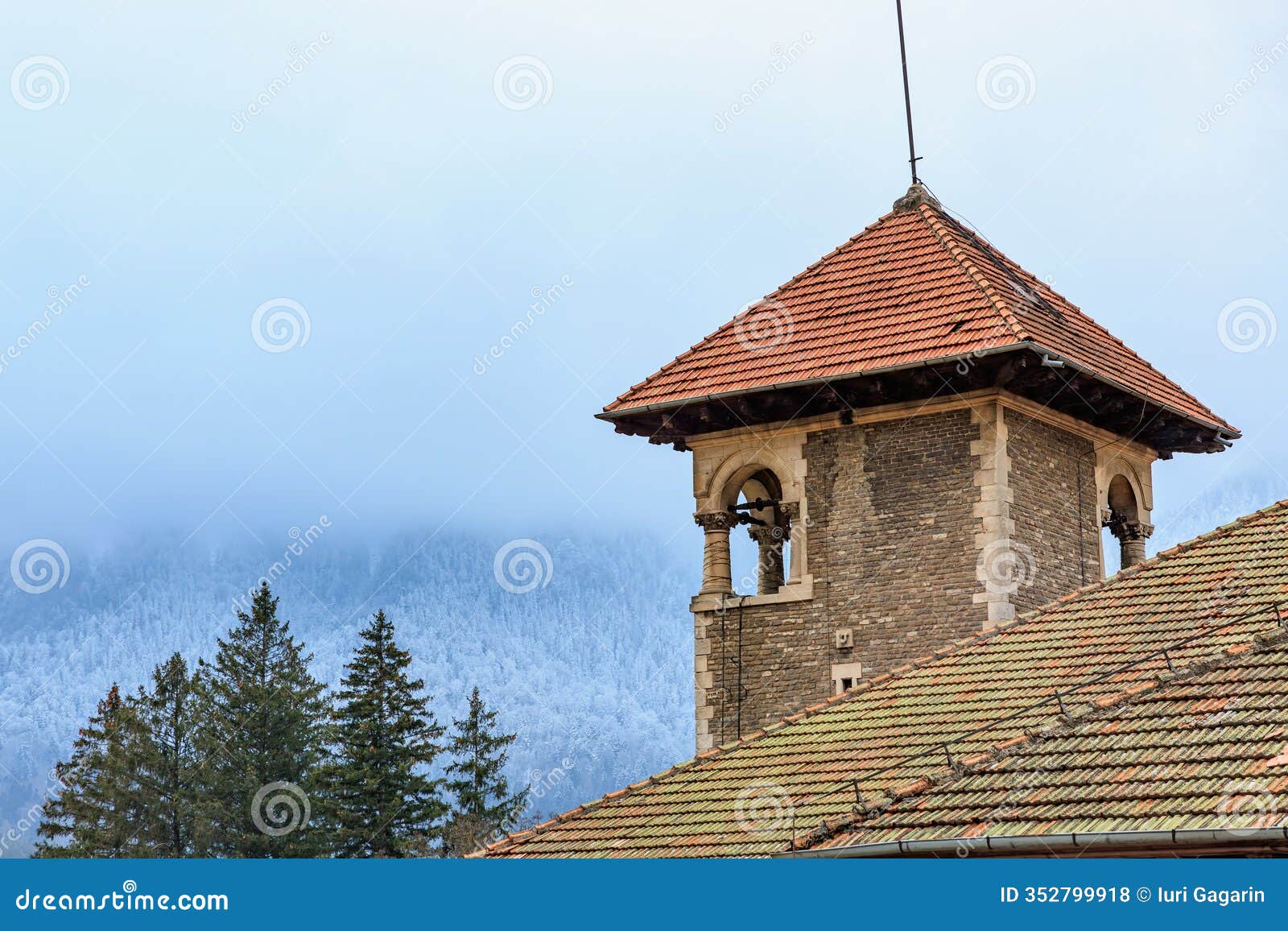 Rustic Stone Clock Tower with Snowy Mountains and Red Tiled Roof Stock ...