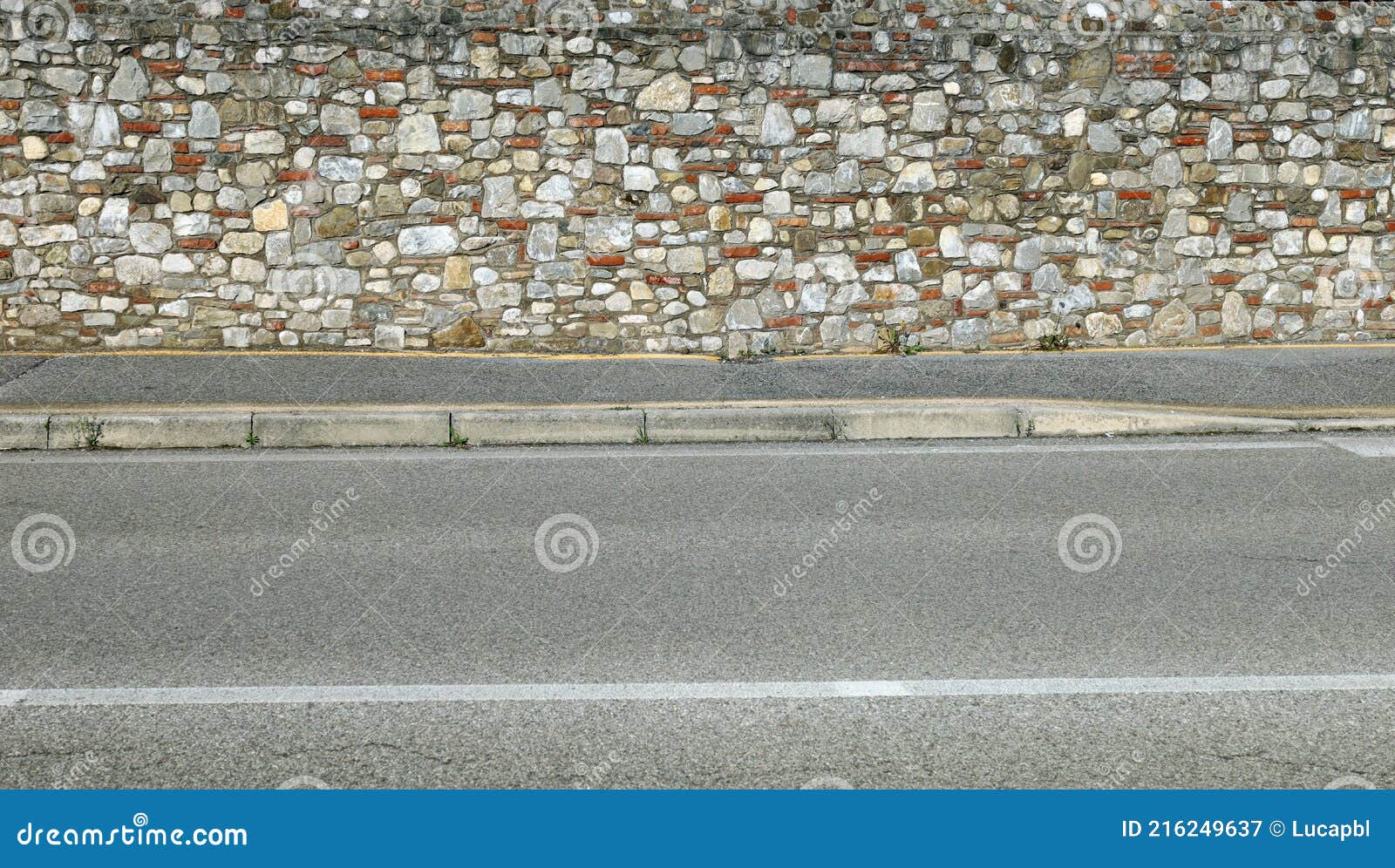 Rustic Stone Wall Made of Rocks and Bricks. a Sidewalk and Asphalt Road ...