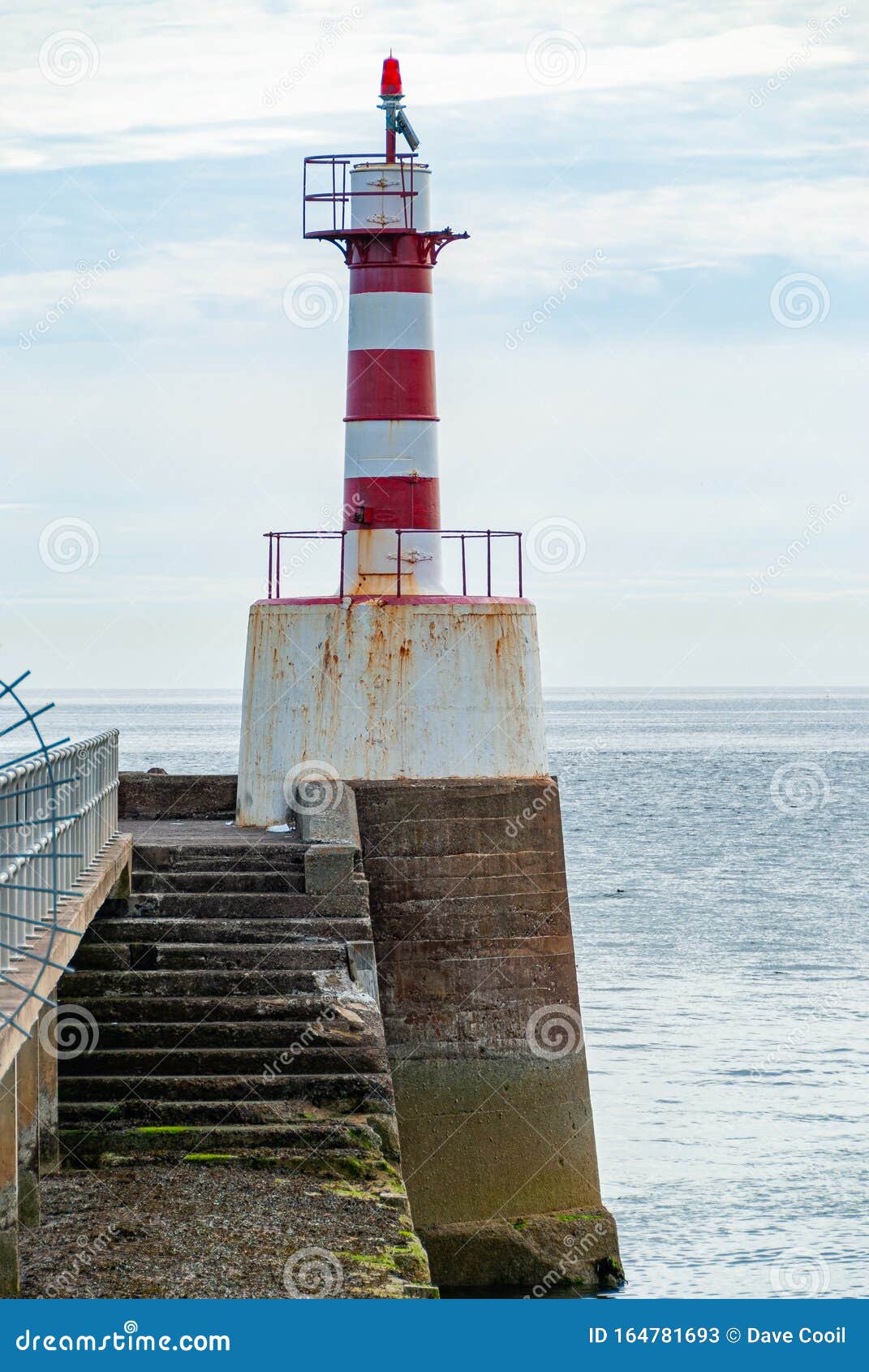 Rusty Old Red and White Striped Harbor Lighthouse at the End of a Jetty ...