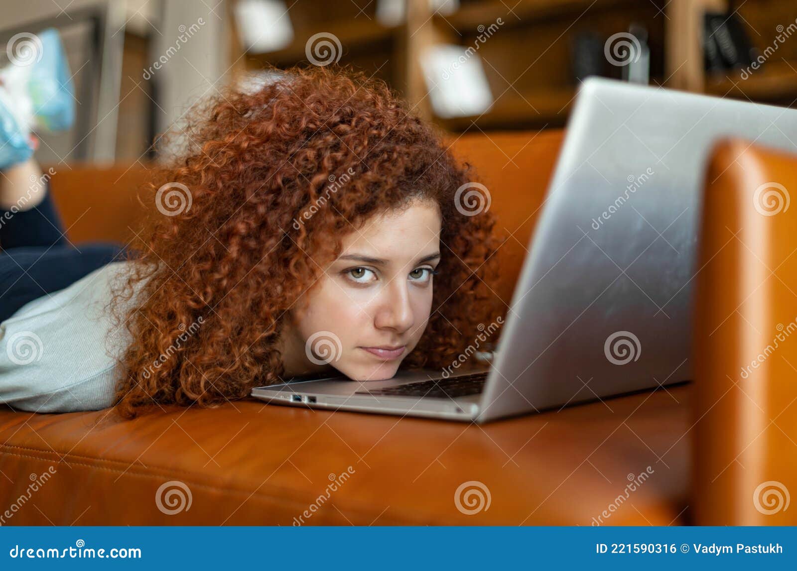 Bored Young Curly Red Haired Woman Lying Down On The Couch In Front Of