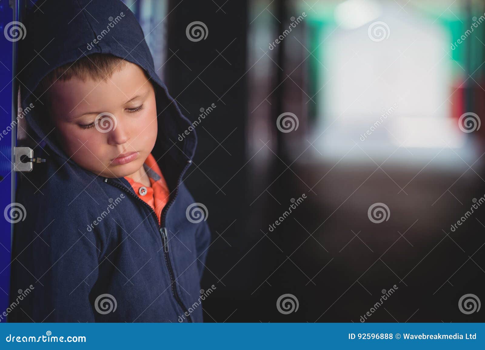 Sad boy leaning on locker stock photo. Image of gloominess - 92596888