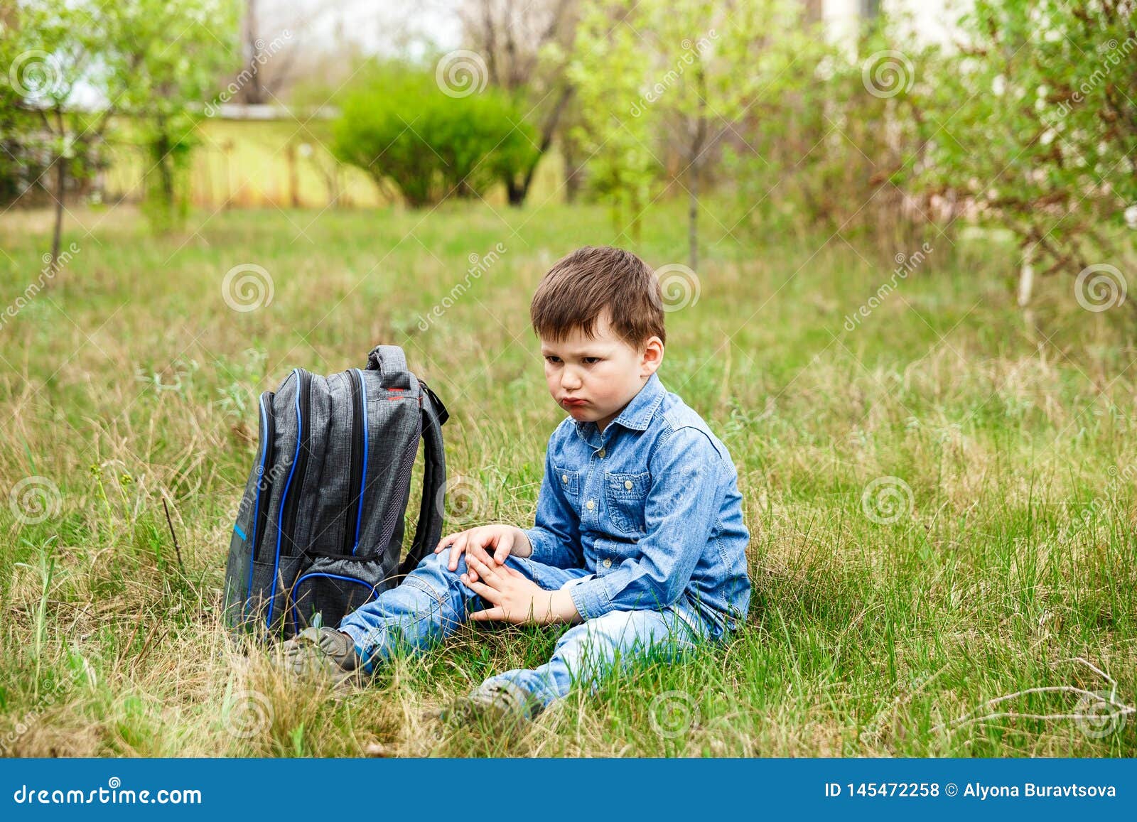 A Sad Little Boy and a Big Backpack on the Green Grass Stock Photo ...