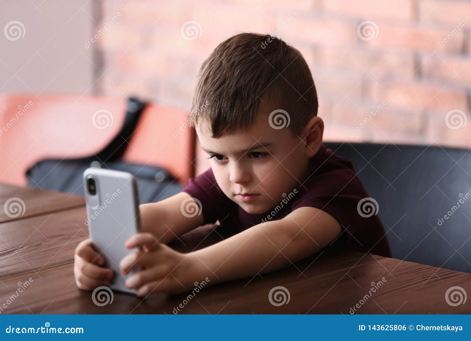 Sad Little Boy with Mobile Phone Sitting at Table Stock Photo - Image ...