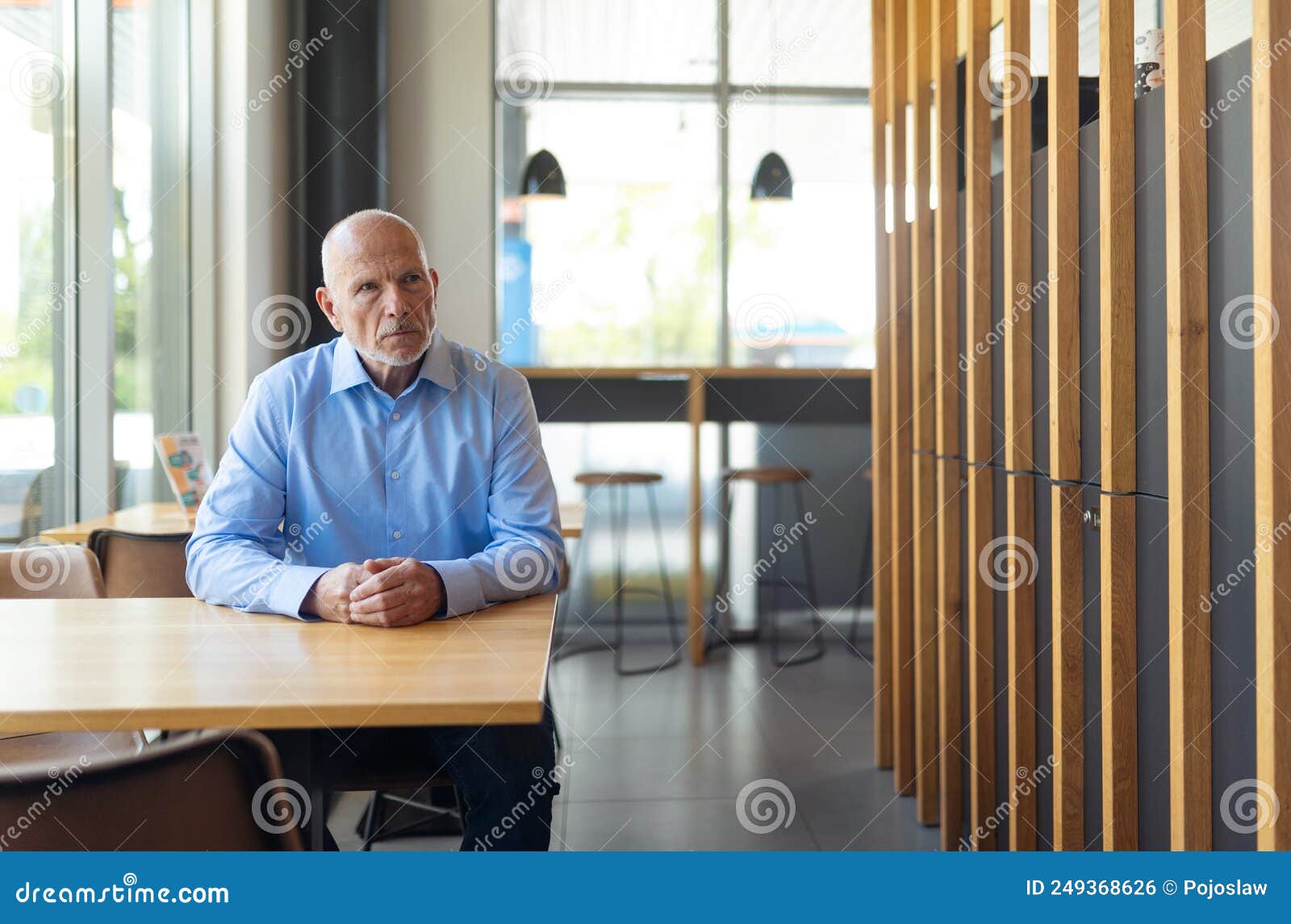 Sad Senior Man Sitting at Empty Table with Blurred Cafe Interior in ...