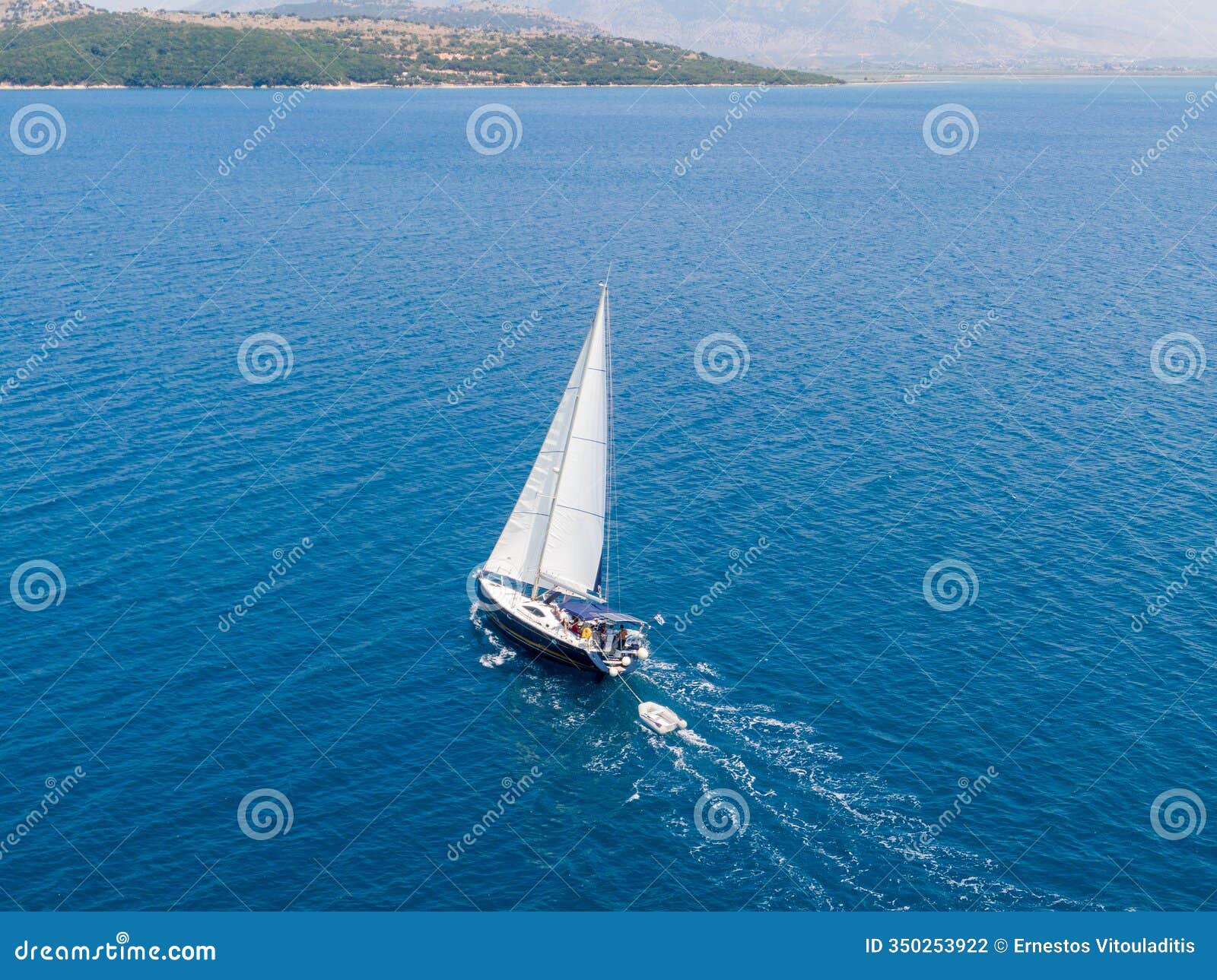 Sailboat on Blue Water with a Small Dinghy Trailing Behind Stock Photo ...