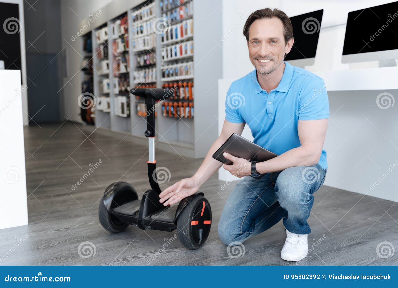 Salesman Posing for Camera with Tablet and Mini Segway Stock Photo ...