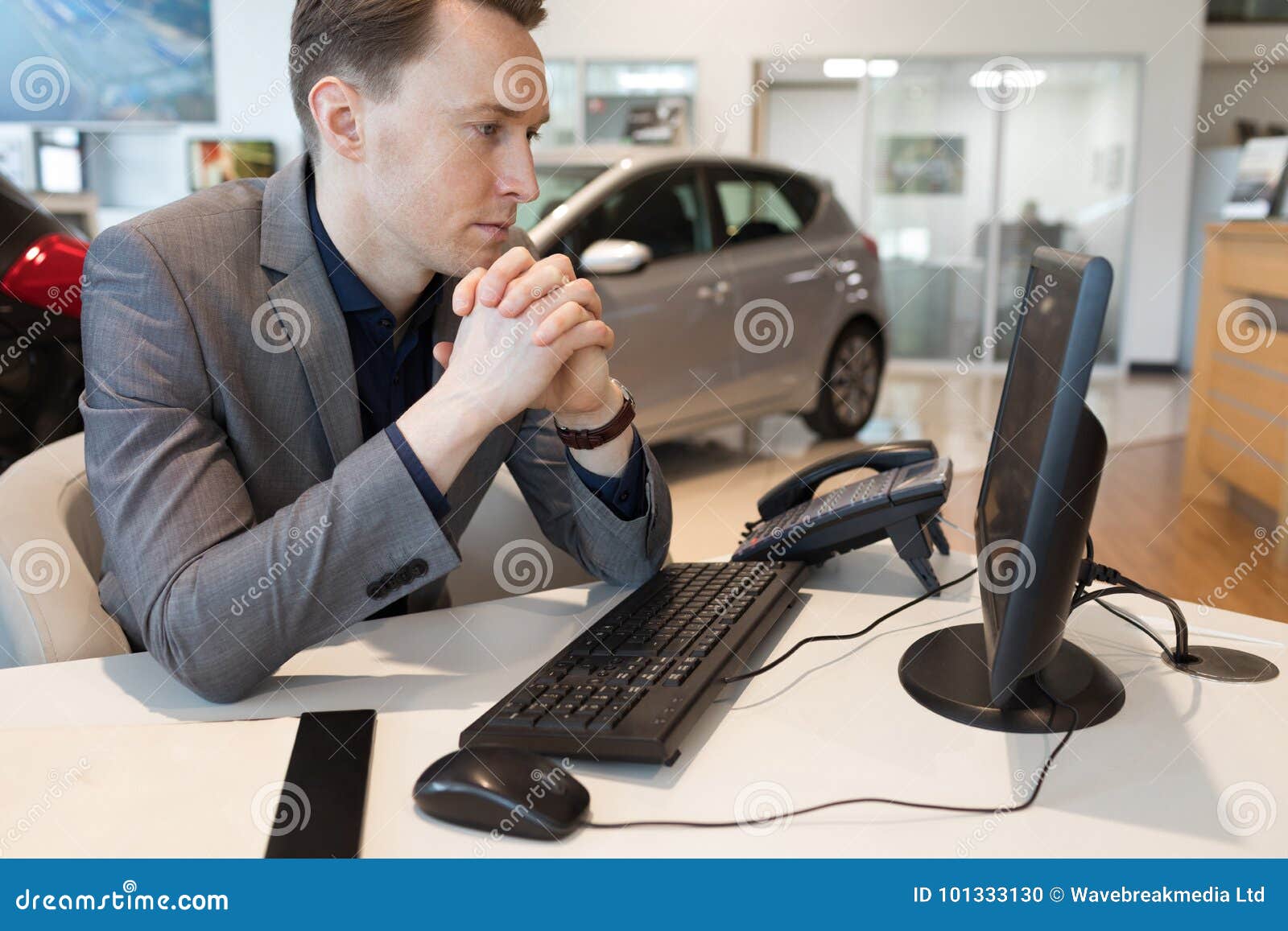 Salesman Using Computer while Working in Car Showroom Stock Photo ...
