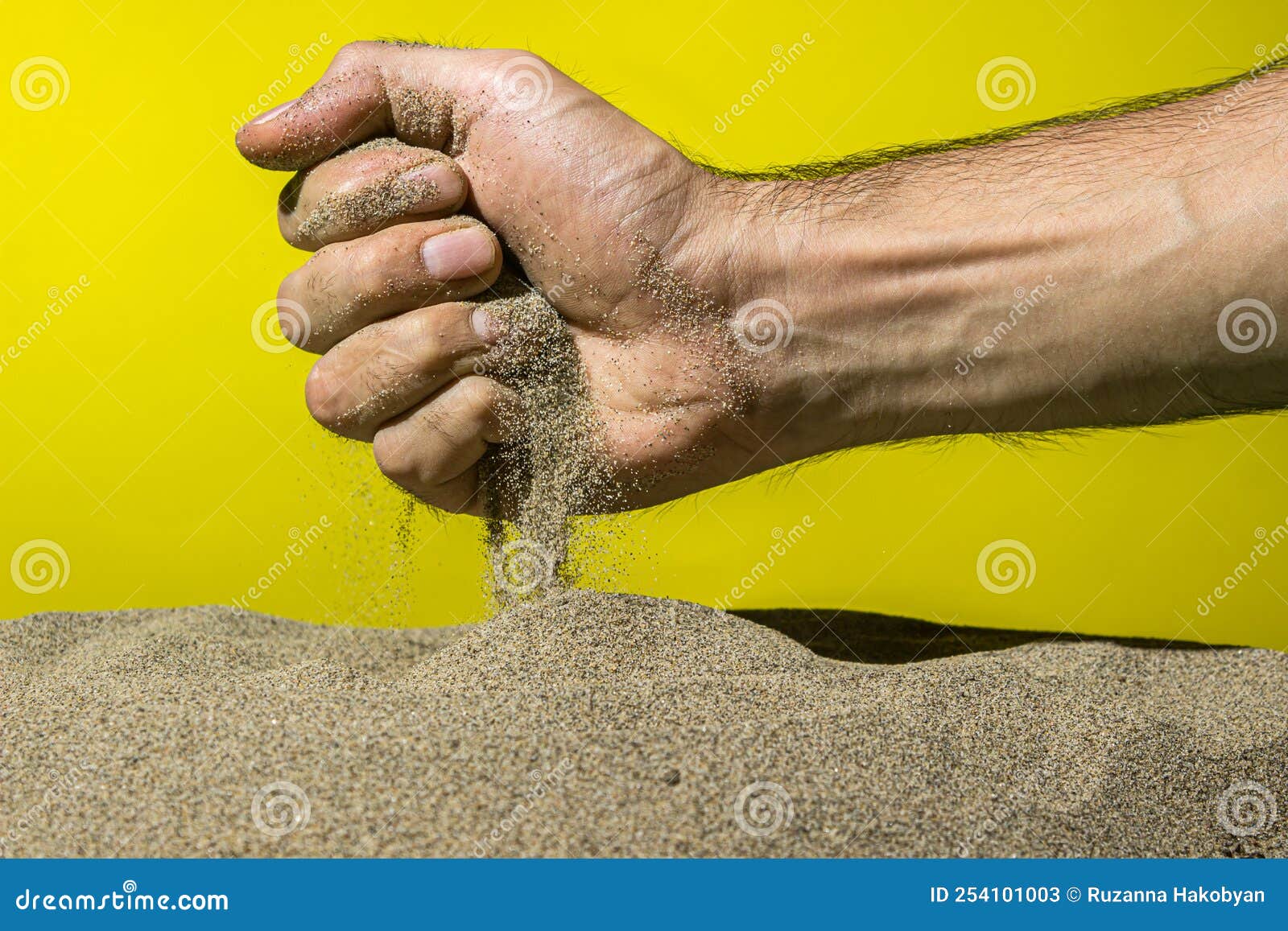 Sand Pours through Fingers on a Yellow Background. Stock Image - Image ...