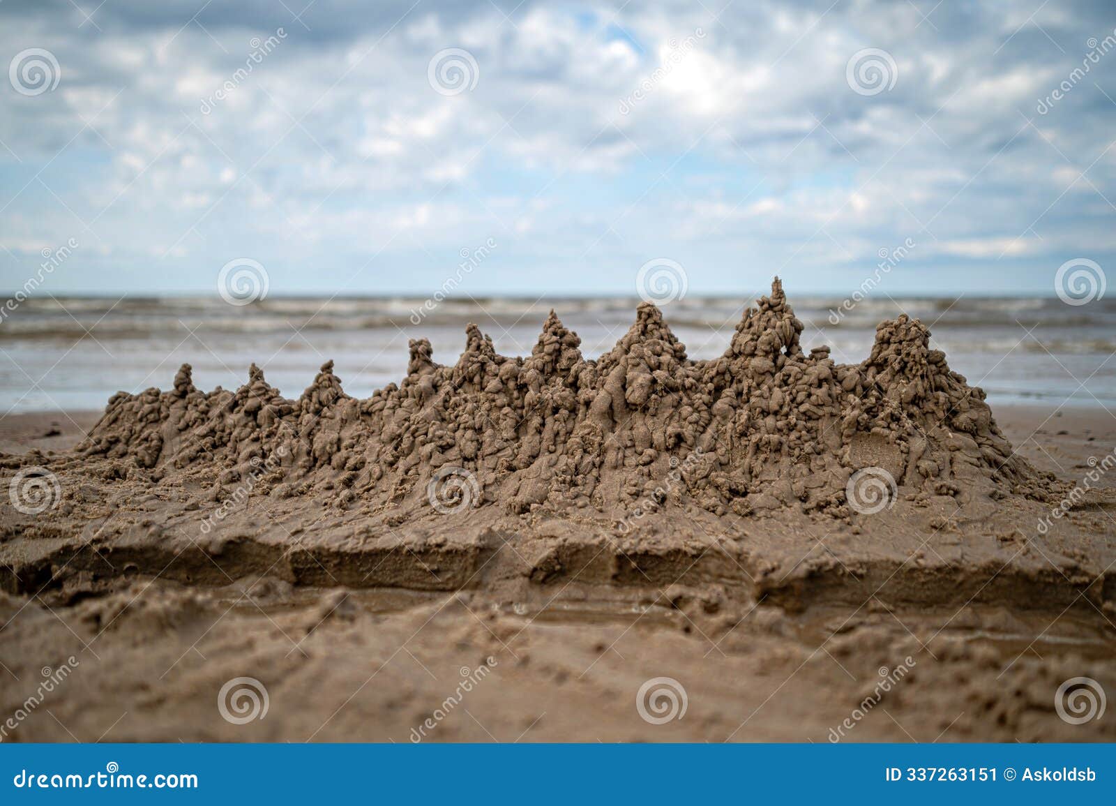 A Sandcastle Stands on the Shore As Waves Gently Lap at Its Base Stock ...