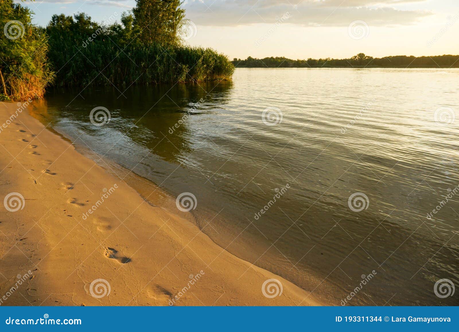 Sandy Riverbank with Footprints in the Sand and Calm River Waters at ...