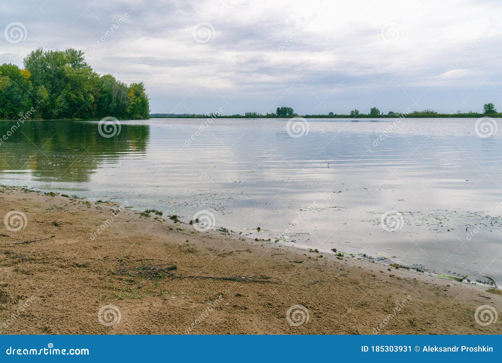 Sandy Shore of the Lake with a Quiet Surface of Water Under Cloudy ...