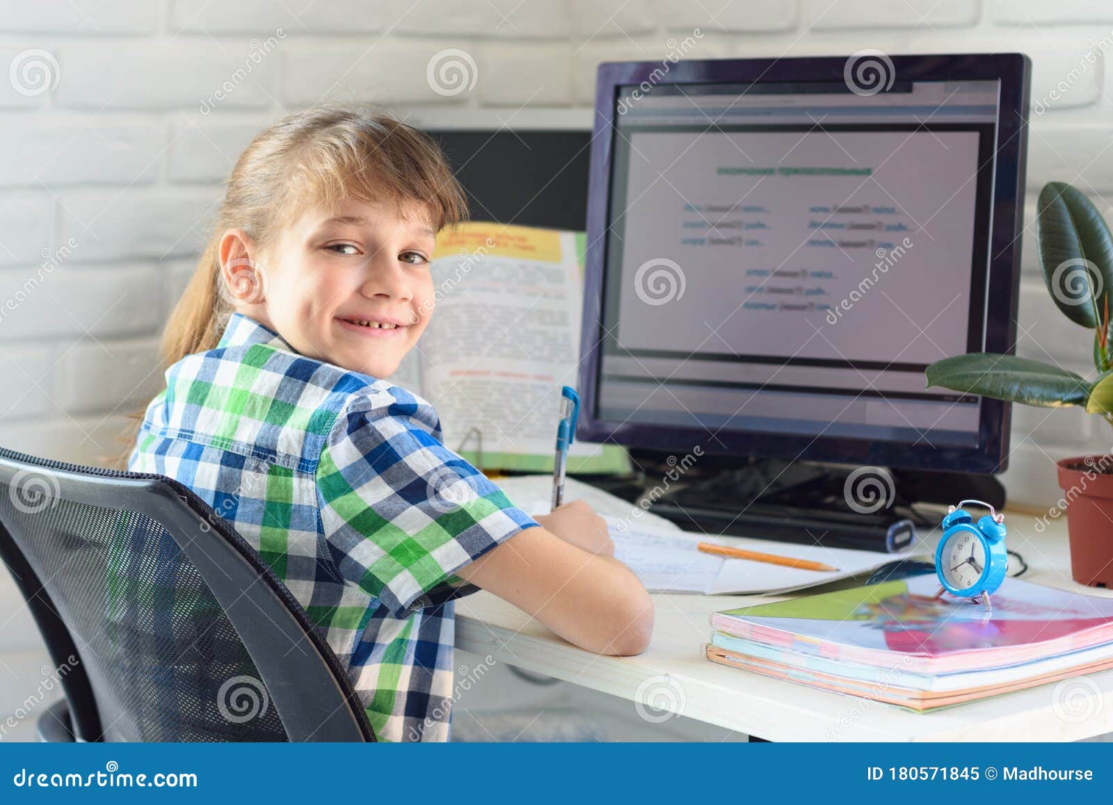 A Satisfied Child Sits at a Computer Table and Looks into the Frame ...