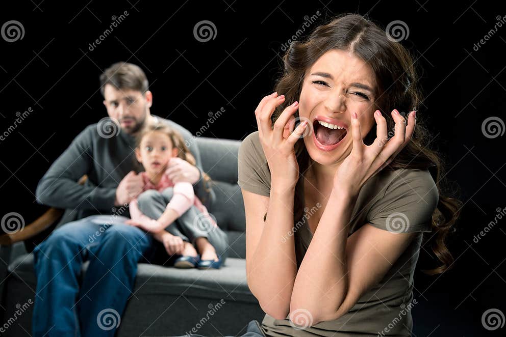 Scared Girl Sitting With Father On Couch While Mother Screaming At