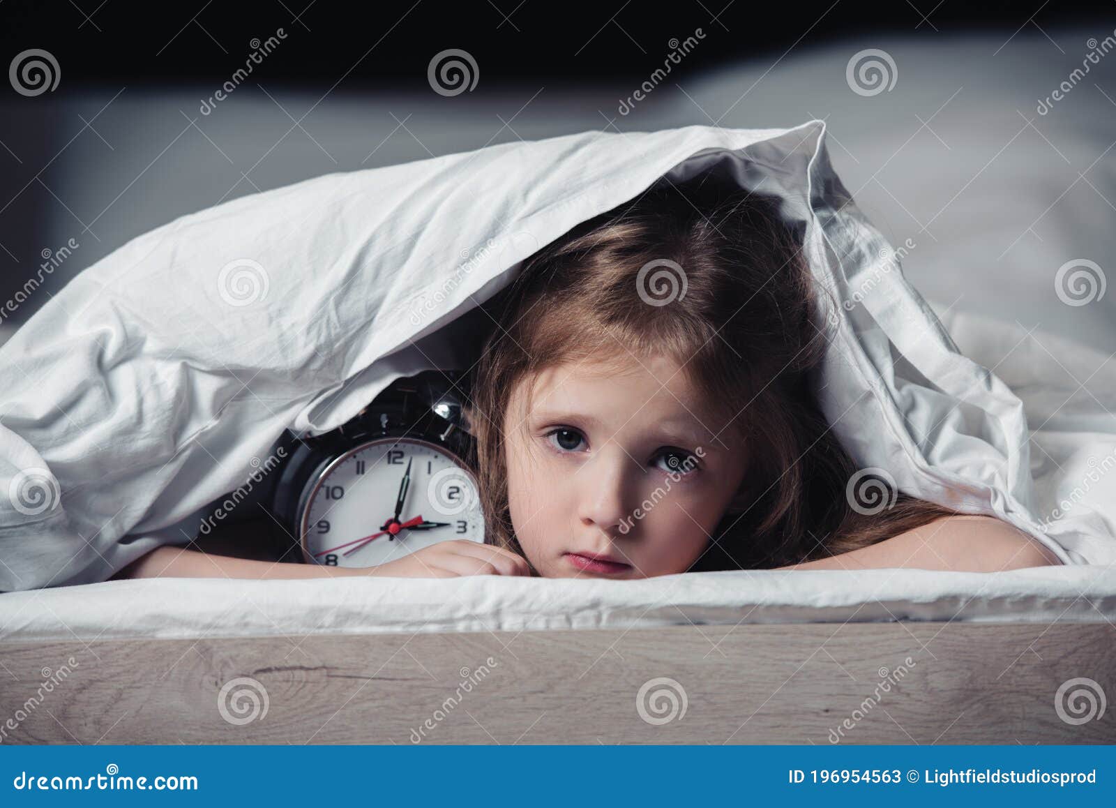 Scared Kid Hiding Under Blanket with Alarm Clock and Looking at Camera ...