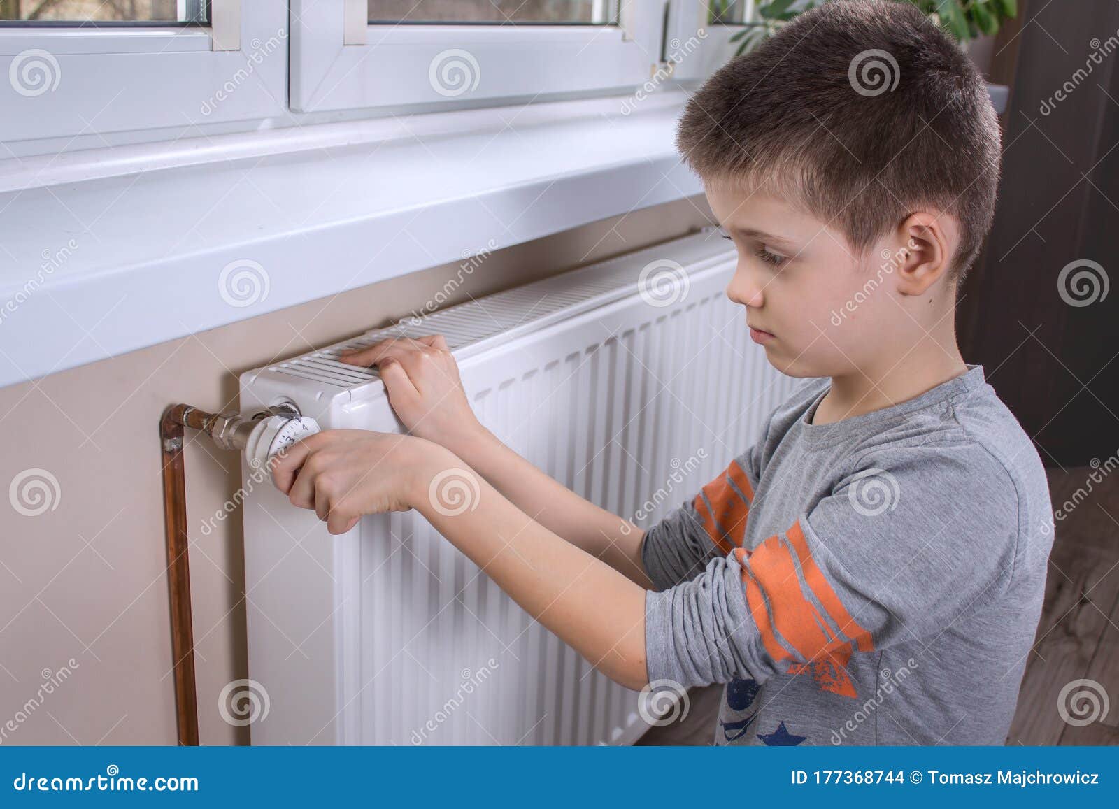 School-age Boy Holds the Temperature Control Knob on the Radiator and ...