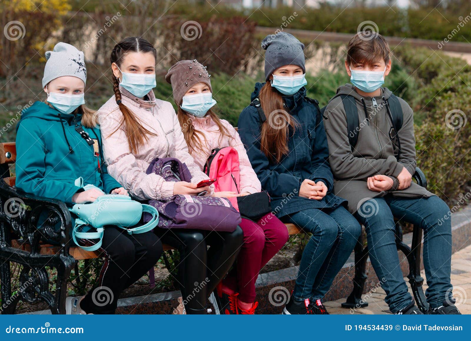 School-age Children in Medical Masks Sit on a Bench. Stock Image ...