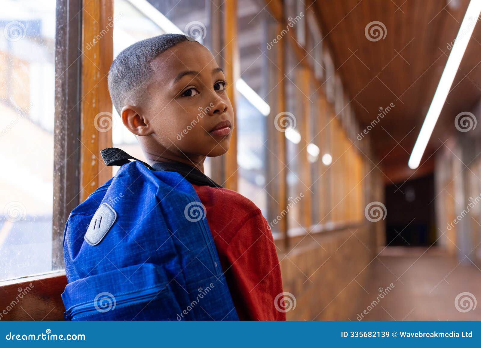 In School, Boy with Blue Backpack Looking Back in Hallway, Thoughtful ...