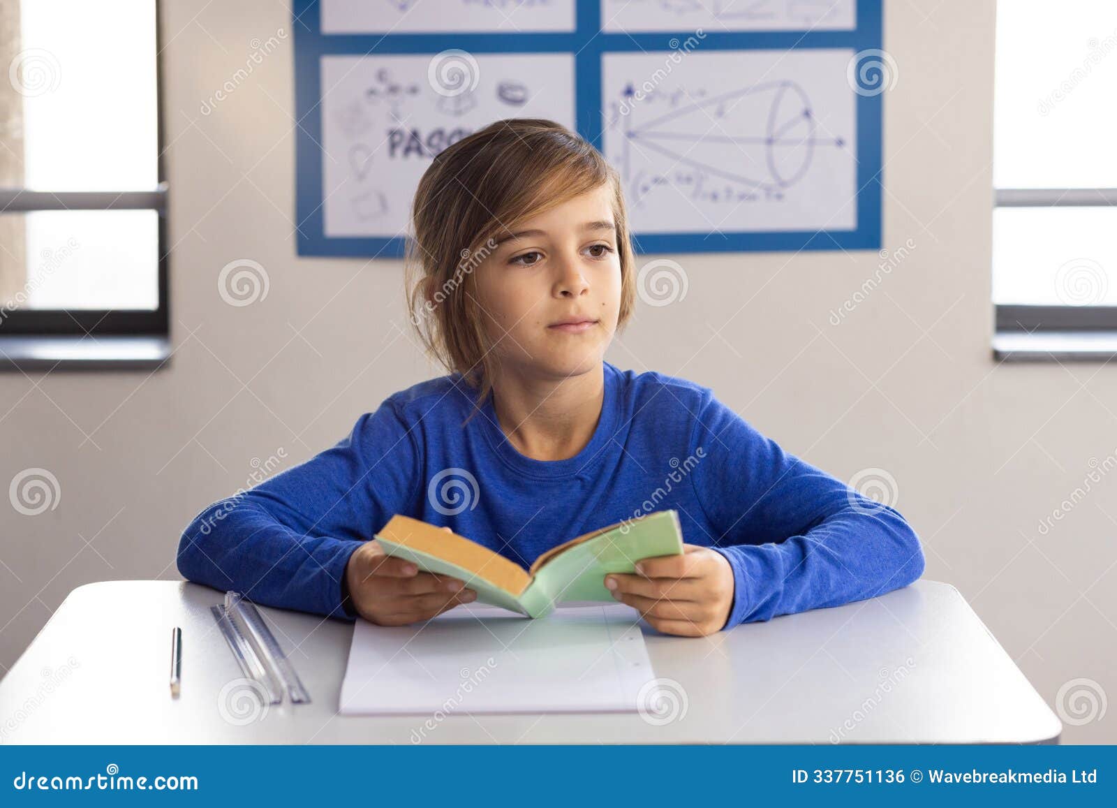 In School, Boy Reading Book at Desk with Notepad and Pens Stock Photo ...