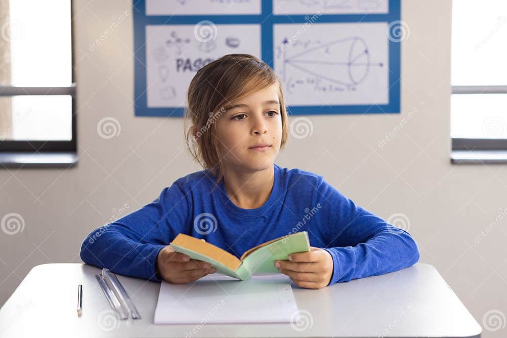 In School, Boy Reading Book at Desk with Notepad and Pens Stock Photo ...