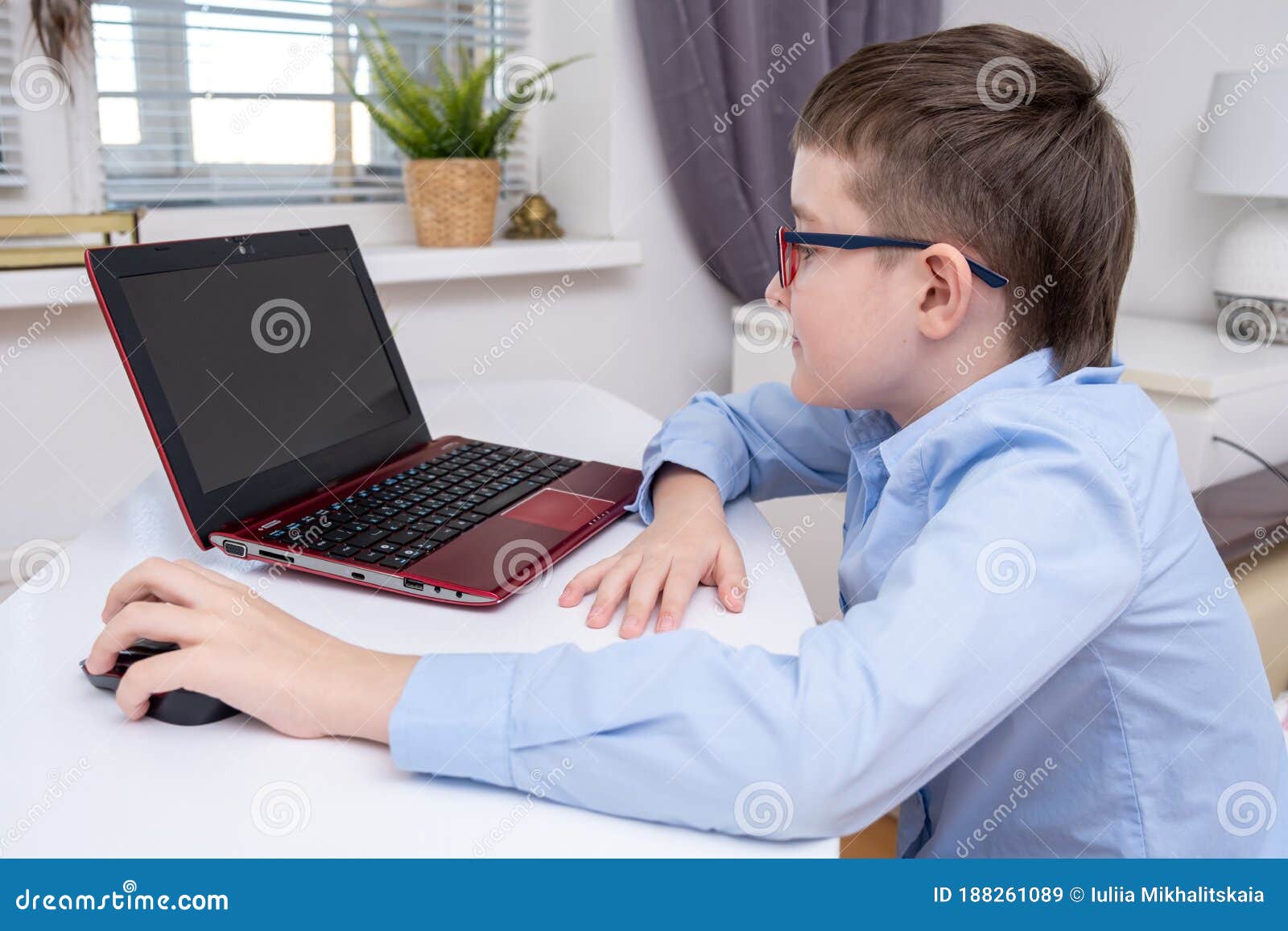 A School Boy Sitting by the Table with a Laptop and Doing Homework, E ...