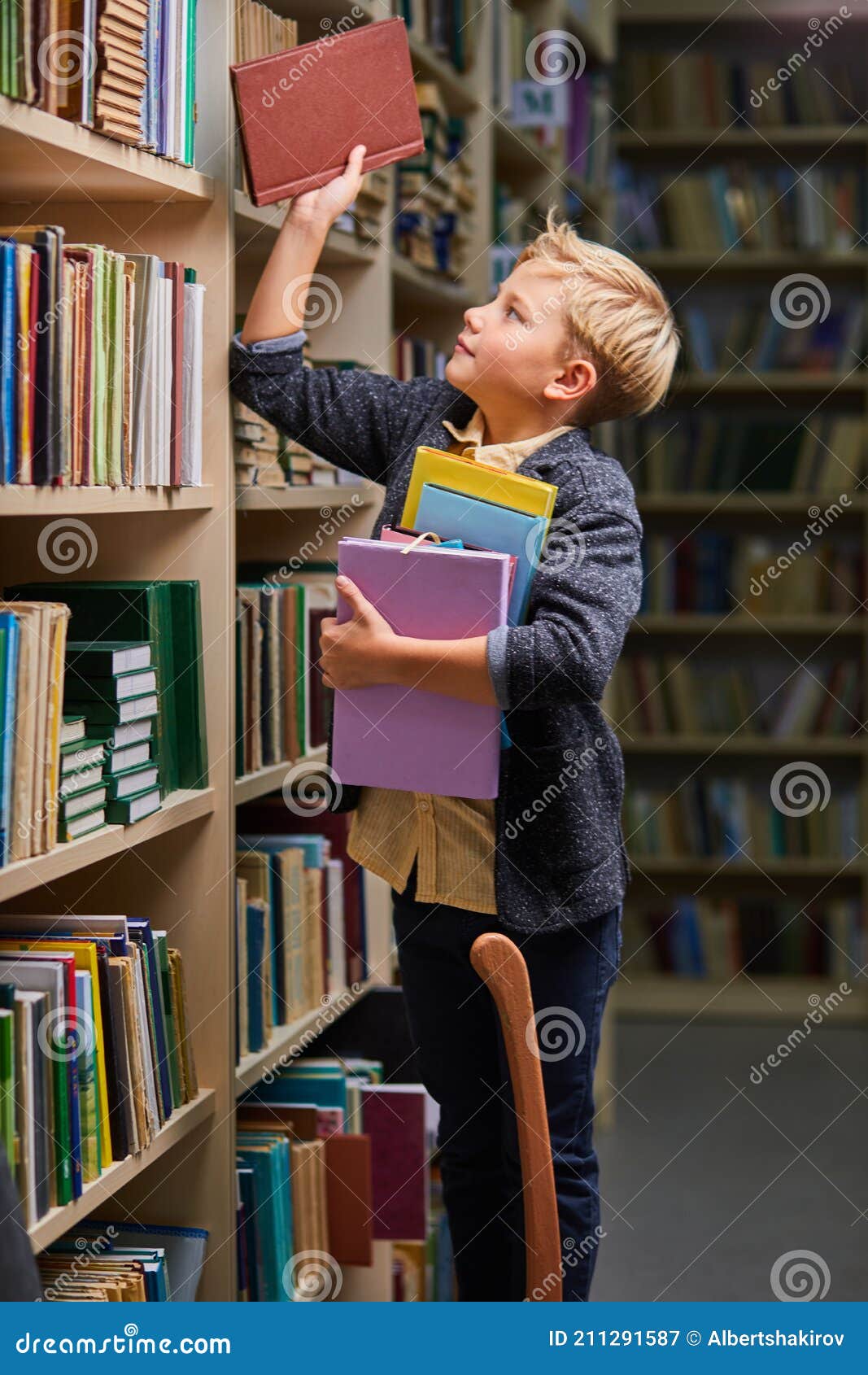 Little School Boy Taking Books from Shelves in Library, with a Stack of ...