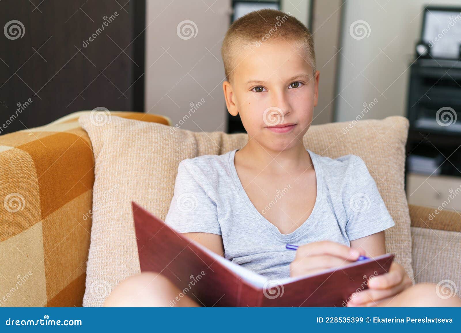 School Days, Boy Solves His Homework on Couch with a Notebook in His ...