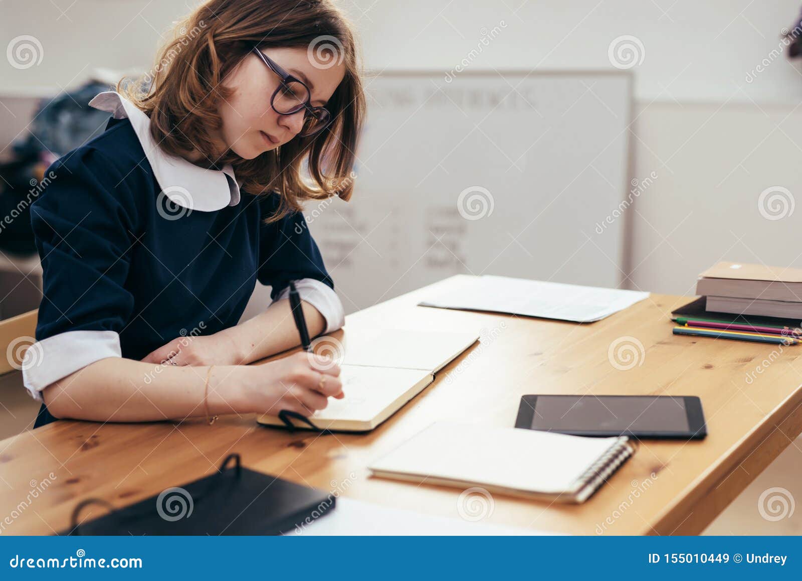 School Girl Writes in a Notebook Sitting at Table Classwork, Homework ...