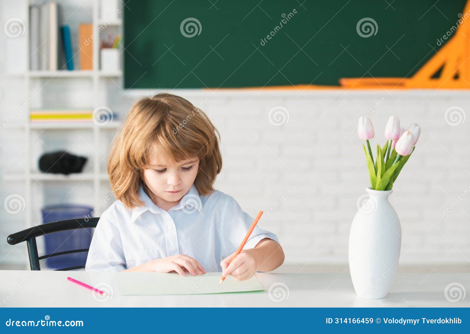 School Kid Writing in Copybook and Sitting at Table in Classroom. First ...