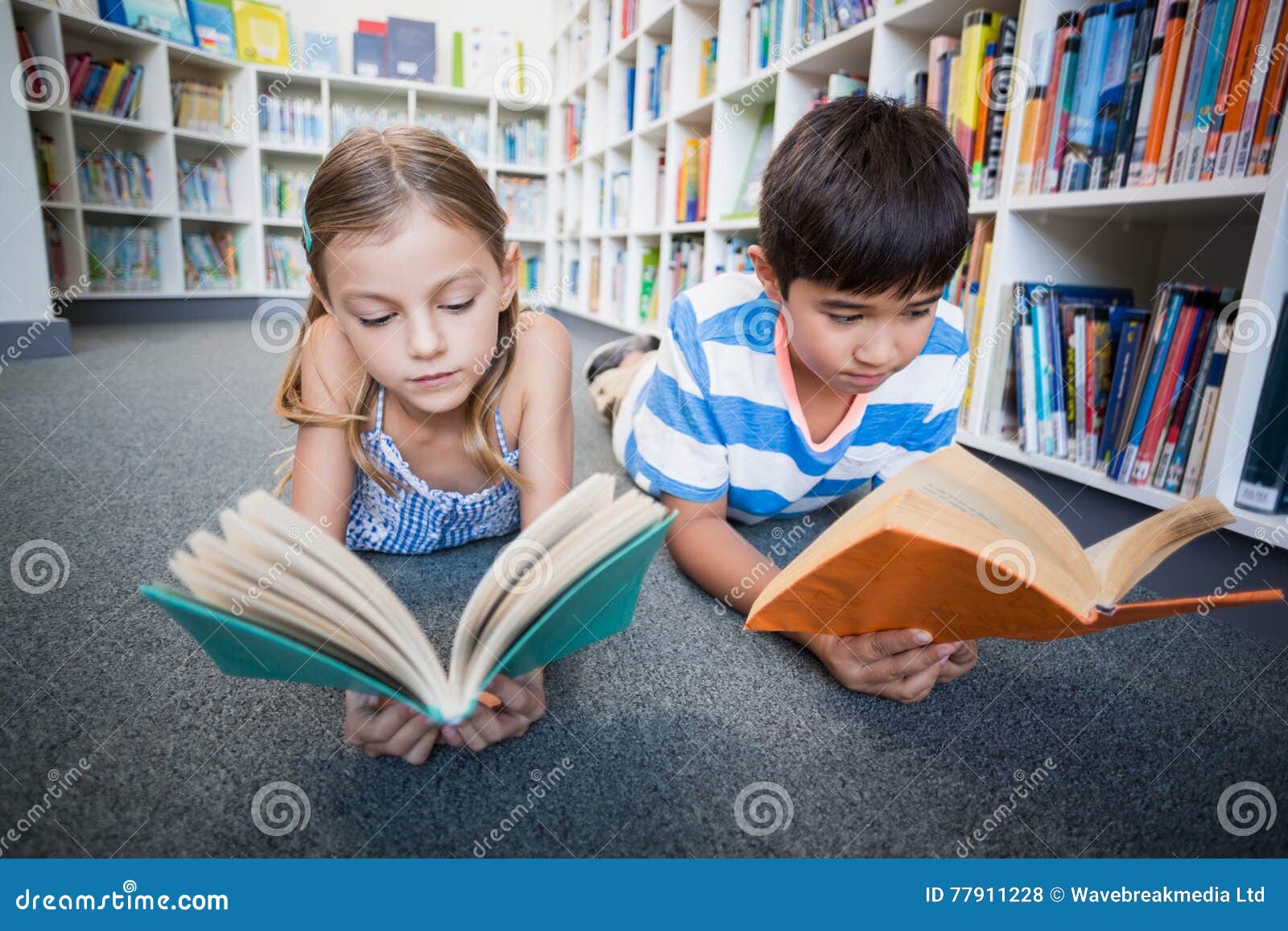 School Kids Lying on Floor and Reading a Book in Library Stock Photo ...