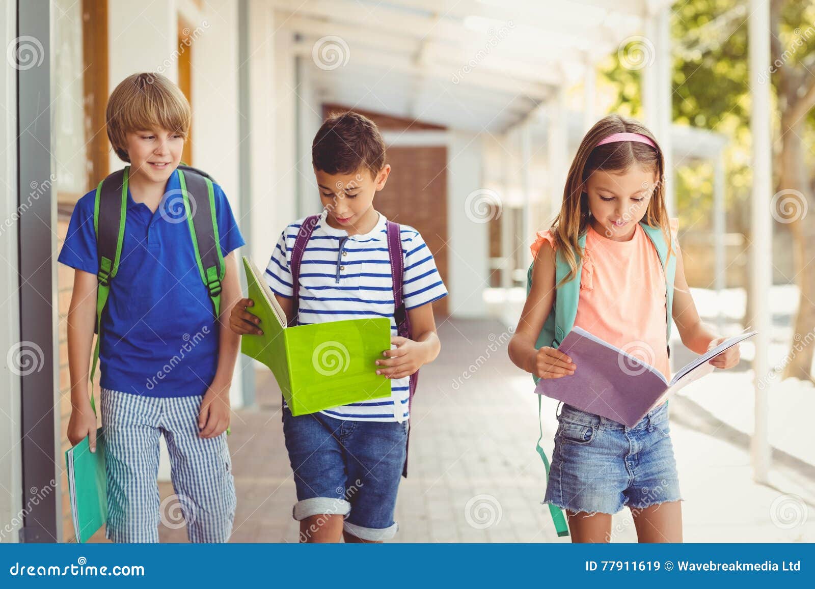 School Kids Reading Books while Walking in Corridor Stock Image - Image ...