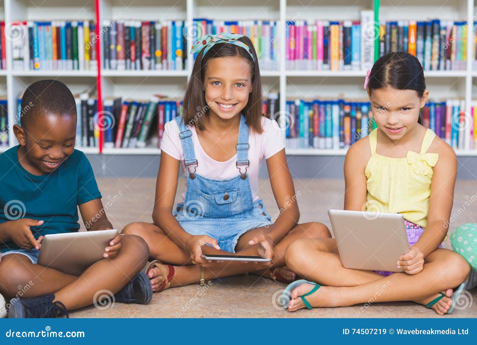 School Kids Sitting on Floor Using Digital Tablet in Library Stock ...