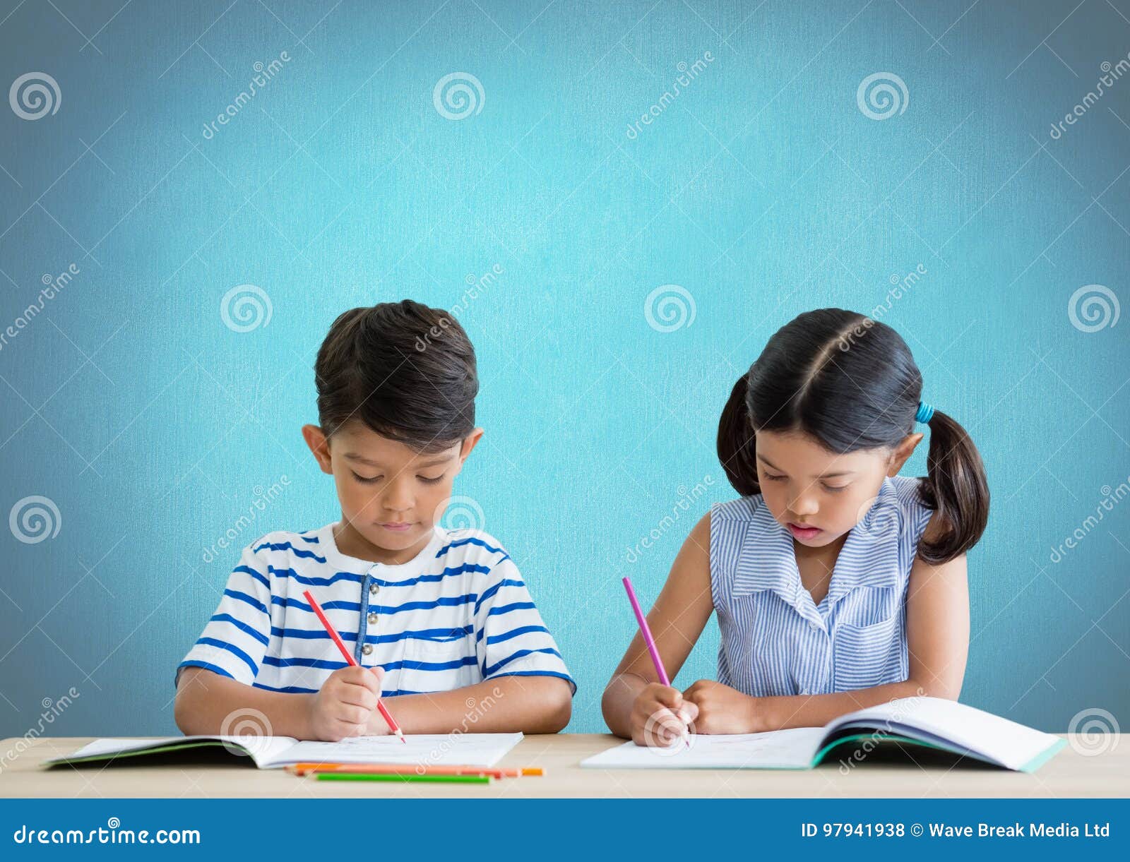 School Kids Writing at Desk in Front of Blue Background Stock Photo ...