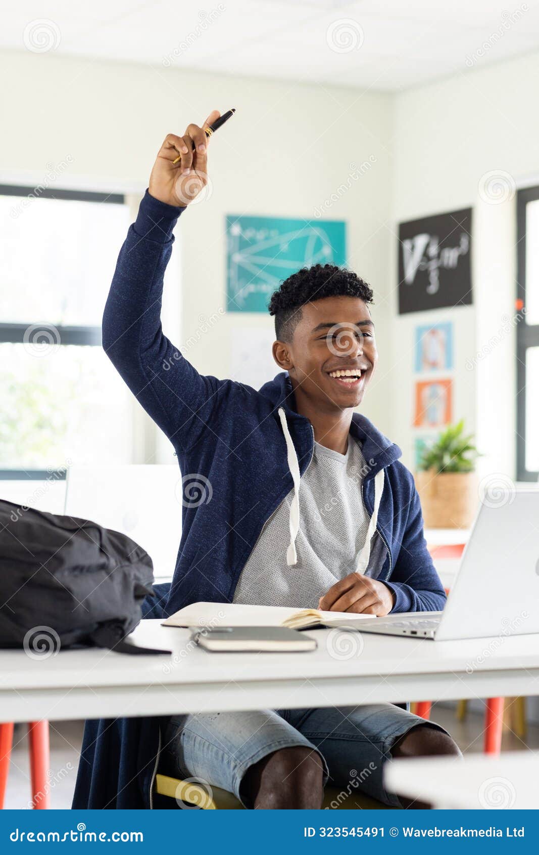 In School, Male Student Raising Hand while Using Laptop in Classroom ...