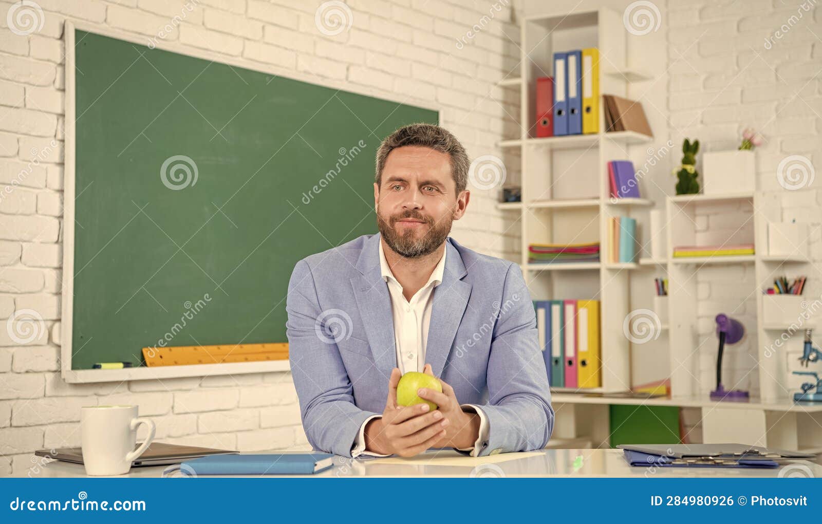 School Teacher Hold Apple in Classroom at Blackboard Stock Photo ...