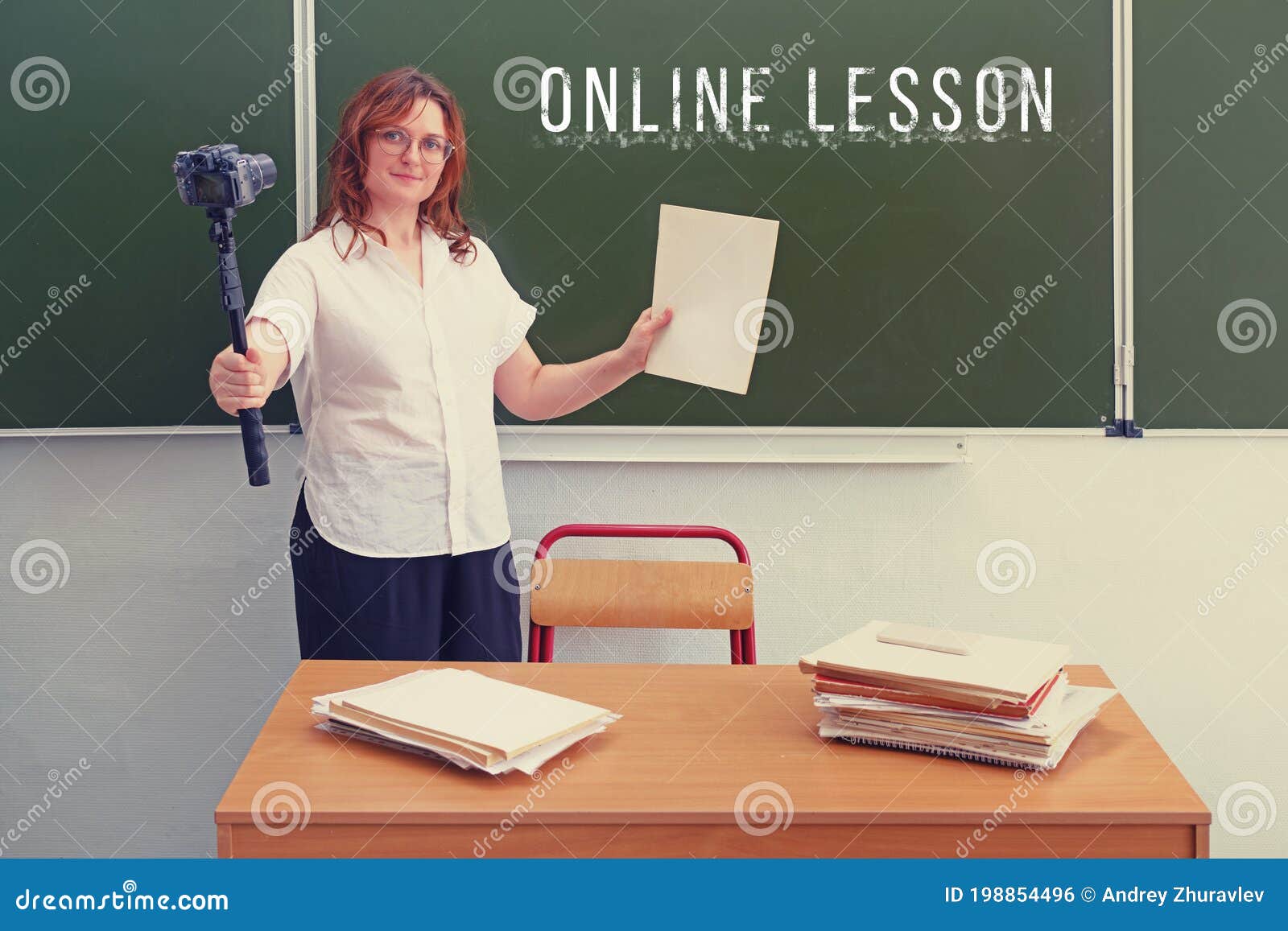 A School Teacher Holds a Camera on a Tripod Standing at the Blackboard ...