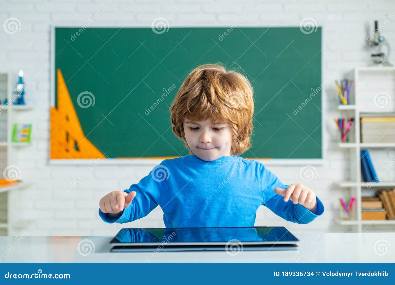 Schoolboy with Digital Tablet in School Classroom. Little Boy Playing ...